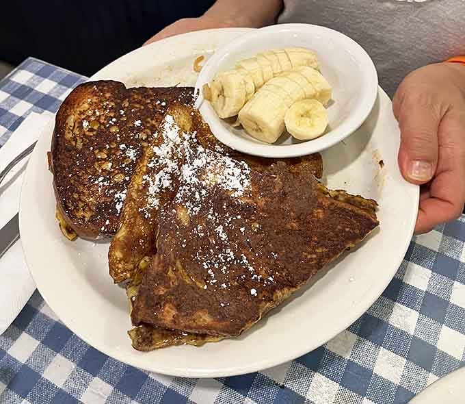 French toast dusted with powdered sugar and served with sliced bananas—simple perfection on a plate every time.