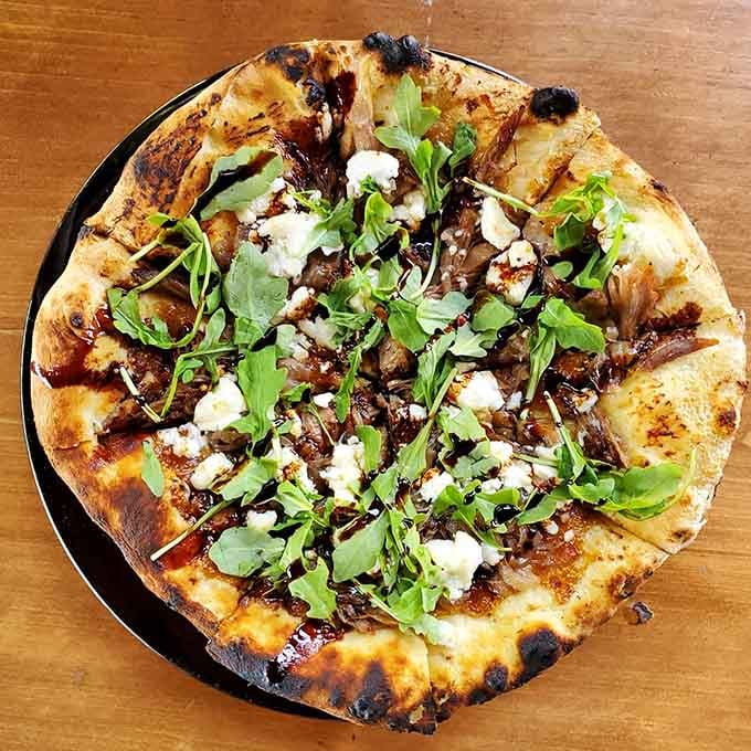 Flatbread topped with arugula and cheese that looks like it belongs in a much fancier zip code.