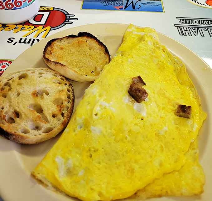 This omelet arrives folded like a fluffy yellow envelope containing all your breakfast dreams and possibly some sausage secrets.