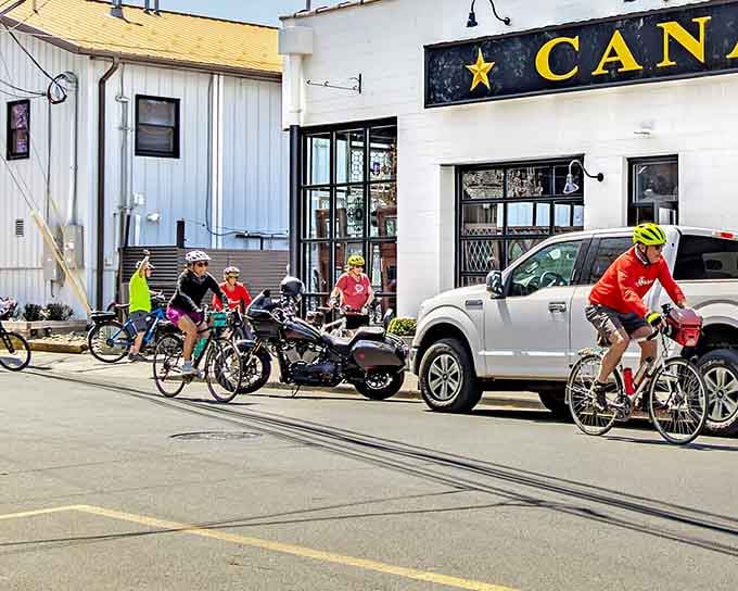 Cyclists cruise past the old canal building, proving small towns can be both historic and surprisingly hip simultaneously.