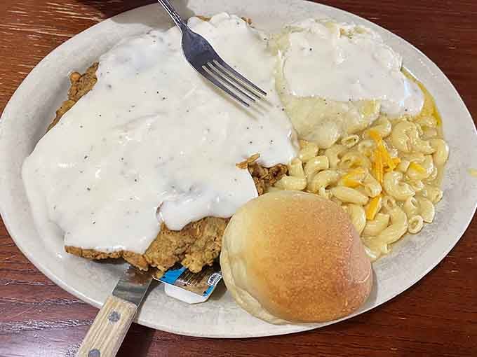 Country fried steak blanketed in white gravy alongside fluffy eggs represents breakfast done absolutely, gloriously right.