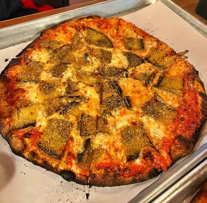 Eggplant pizza with that perfect char pattern shows why coal-fired ovens are worth the hype.