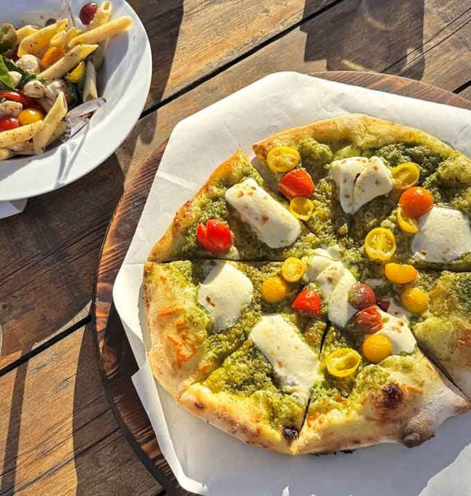Wood-fired pizza topped with pesto and fresh mozzarella, proving that simple ingredients make the best culinary magic happen.