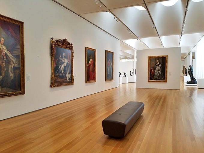 Classic European paintings line pristine white walls, offering a quiet moment to contemplate centuries of artistic genius and craftsmanship.