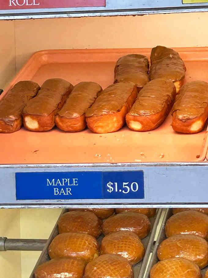Rows of maple bars lined up like soldiers, each one a masterpiece of fried dough and sweet frosting.