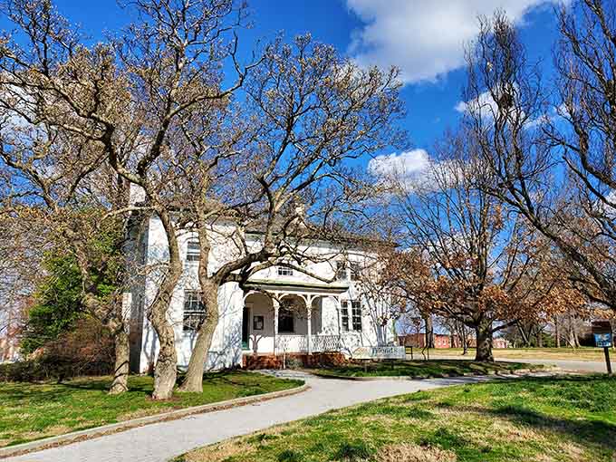 The historic white building nestled among bare trees serves as a charming reminder of the park's long community legacy.