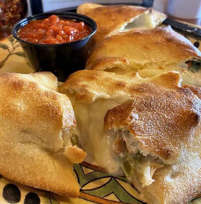That calzone is oozing cheese like a delicious volcanic eruption you actually want to witness up close.