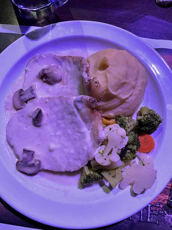 Pork chops with mushroom gravy and vegetables, proving dinner theater food has evolved beyond mystery meat and prayers.