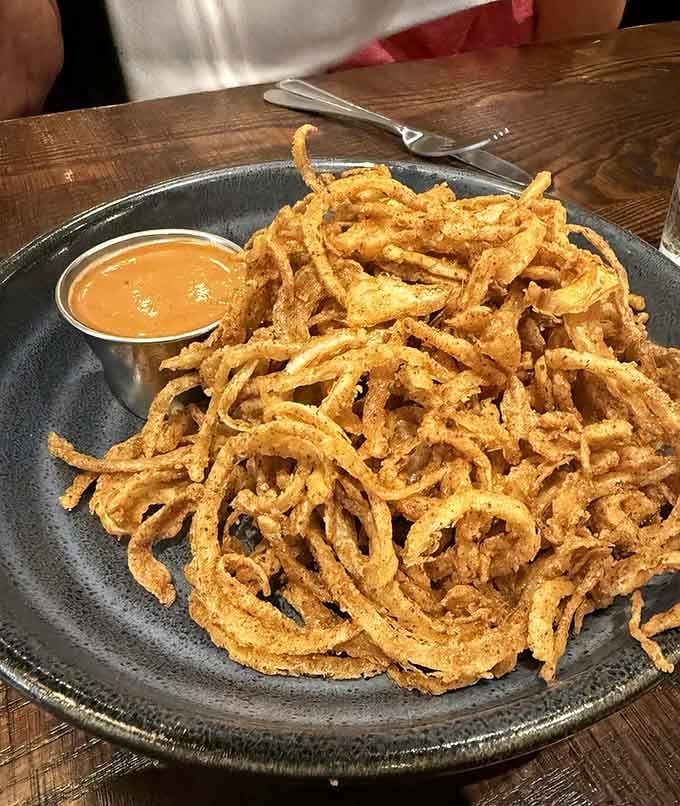 Crispy onion strings piled high enough to make you question whether sharing is really necessary after all.