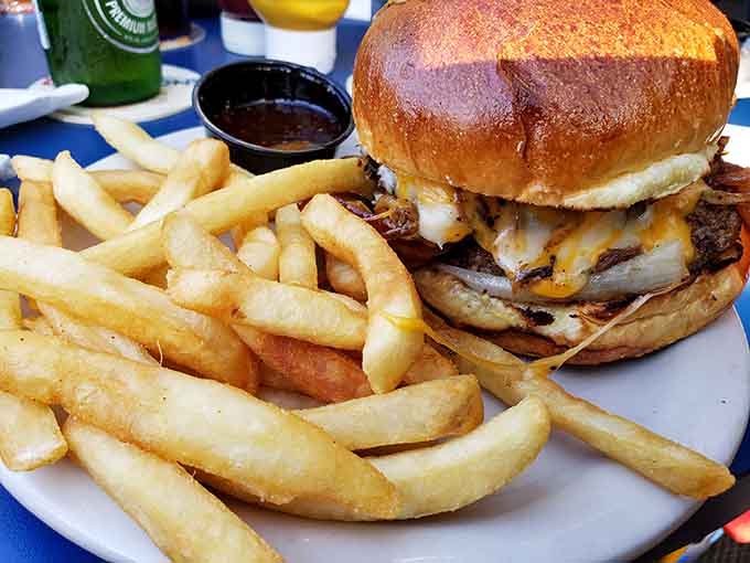 That burger sits there like it owns the place, stacked high with cheese and caramelized onions demanding attention.