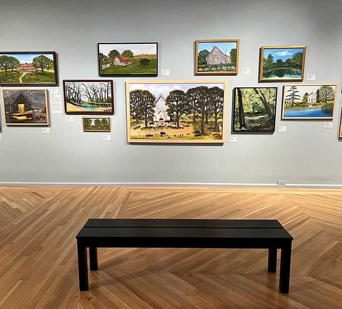 Kentucky landscapes line the walls above a simple bench, proving local artists capture home with remarkable skill.