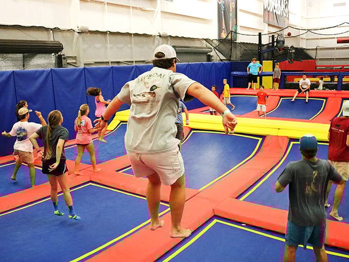 Dad's getting serious air time on the red and blue trampolines while the kids watch in amazement.