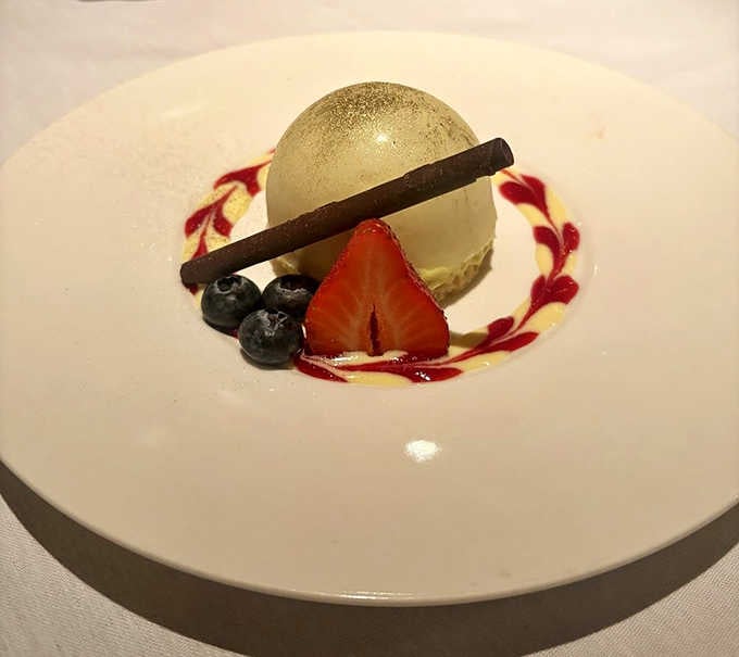 A pistachio dome dessert that's basically edible architecture, complete with fresh berries and a chocolate cigarette for dramatic effect.