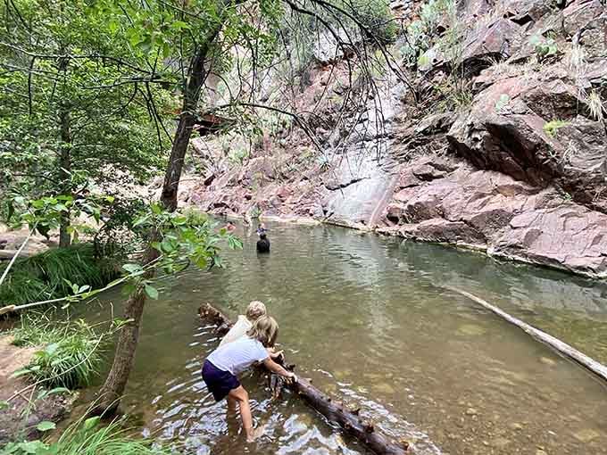 Creek waters meander past towering cliffs where adventurous souls wade through nature's own private swimming hole.