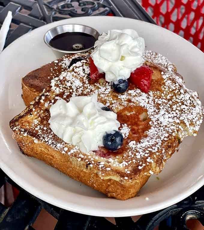 French toast dusted with powdered sugar, topped with berries and cream, basically edible happiness on a plate.