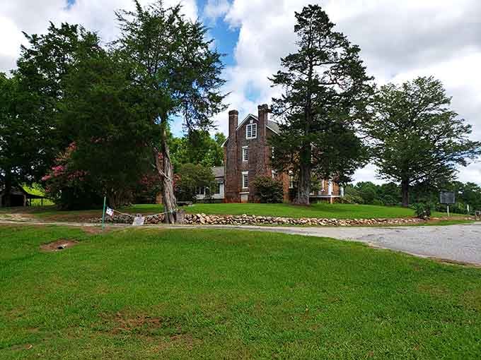 The historic brick home sits peacefully among the trees, holding stories that shaped this community through generations of change.