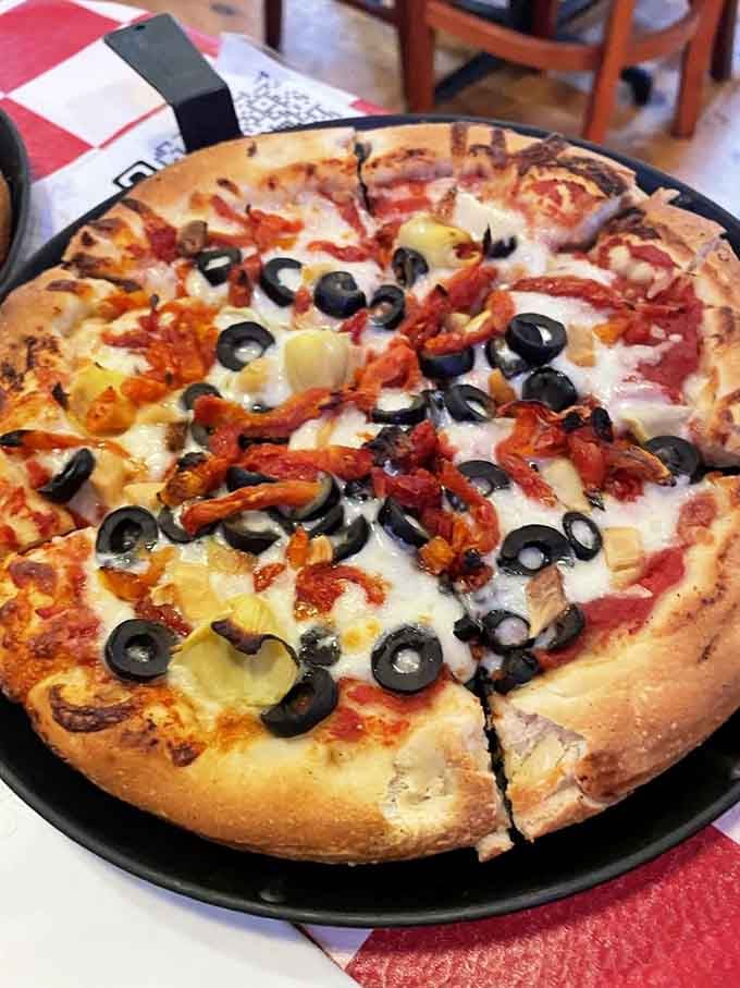 Black olives and colorful toppings transform this California-style pizza into a work of edible art worth photographing.