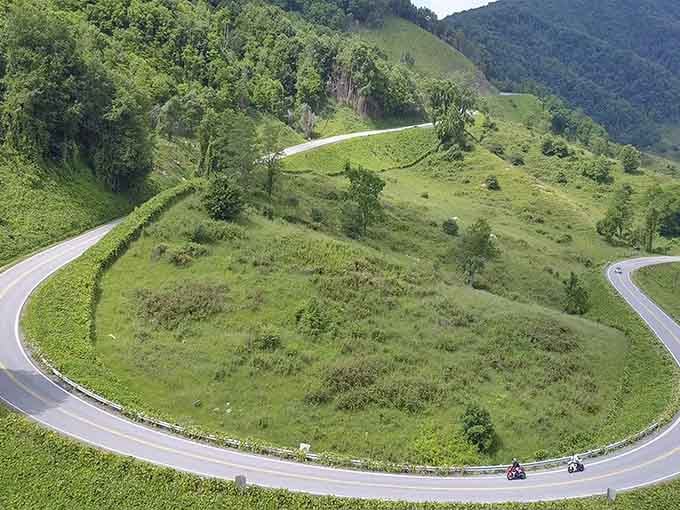 One motorcycle tackles this hairpin turn while the green mountains watch like patient, ancient spectators all around.