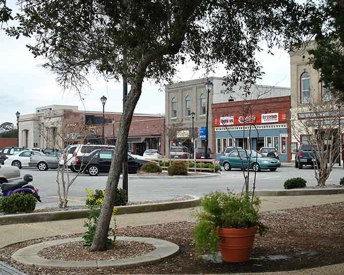 Mature trees shade the town square where planters overflow with flowers and benches invite lingering conversations.