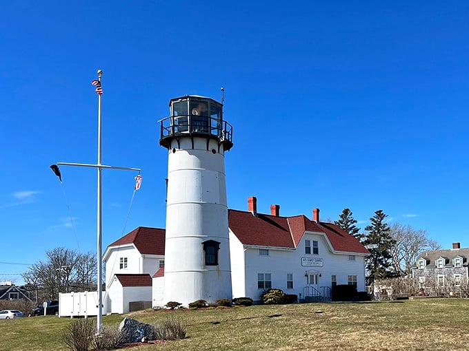 Historic Chatham Lighthouse stands tall before a red-roofed station, offering you a timeless glimpse into the maritime heritage of Massachusetts.