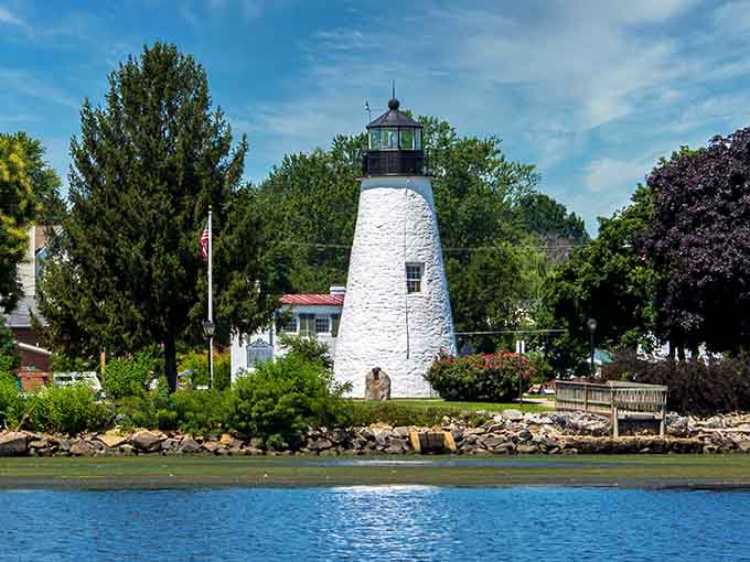 This white stone lighthouse stands cheerful and bright against the water, a beacon of hope and heroism.