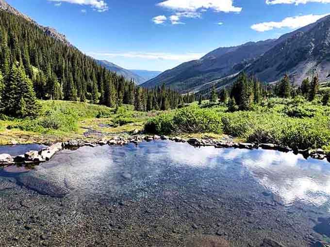 Crystal-clear alpine pools reflect mountain peaks perfectly, offering weary hikers nature's own hot tub with million-dollar views.