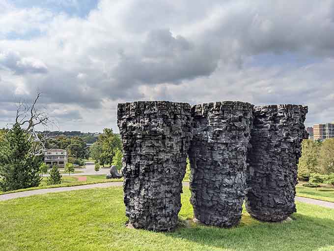 Three textured columns rise from the grass like ancient ruins reimagined, their weathered surfaces telling silent stories.