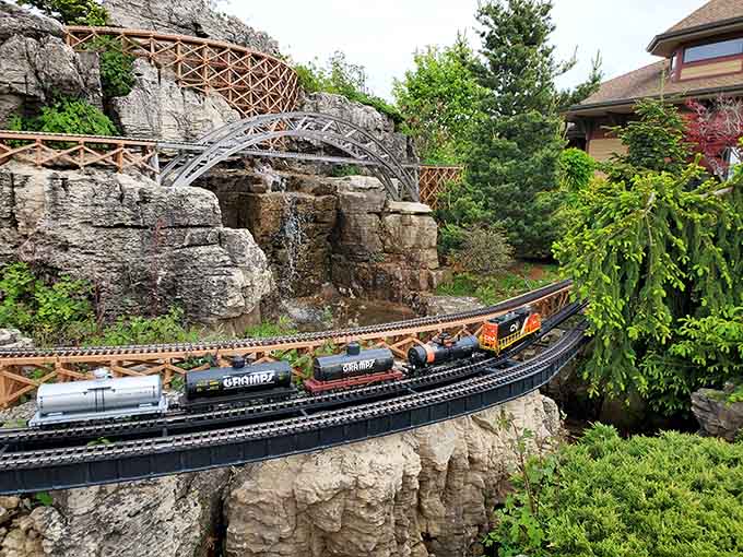 Miniature trains wind through rocky landscapes where waterfalls cascade and bridges span canyons in this enchanting railway garden world.