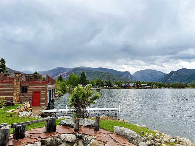 Mountain reflections shimmer across the calm water while cozy lakeside retreats dot the peaceful shoreline.