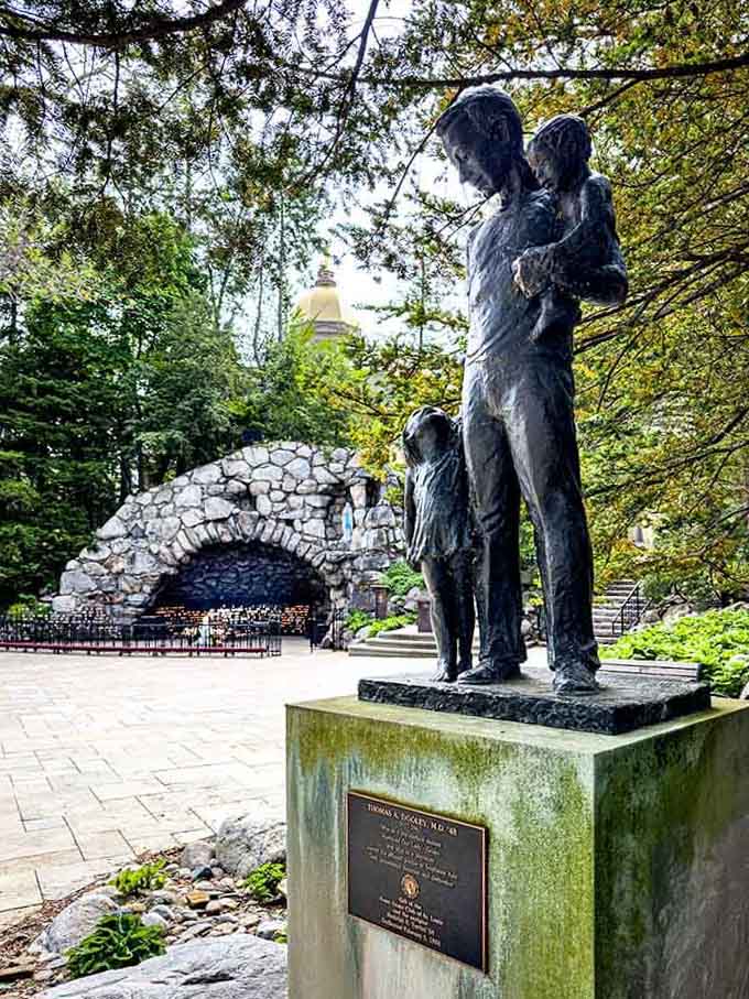 A bronze family statue stands before the grotto's stone arch, capturing a moment of tenderness frozen beautifully in time.