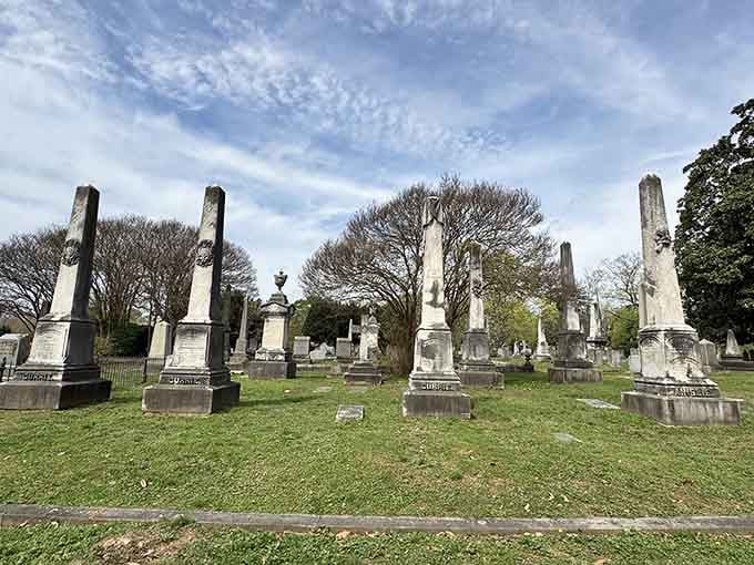 Towering monuments stand sentinel across rolling grounds where history rests beneath centuries-old trees and open sky.