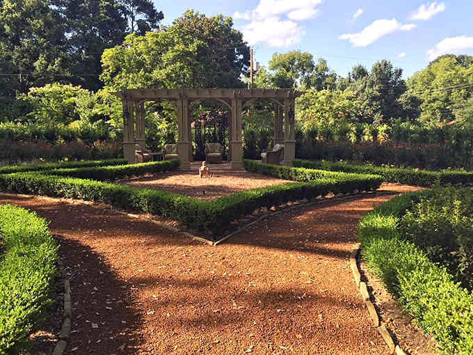 Manicured pathways lead through formal gardens to a peaceful gazebo, where Victorian elegance meets carefully tended Southern landscaping traditions.