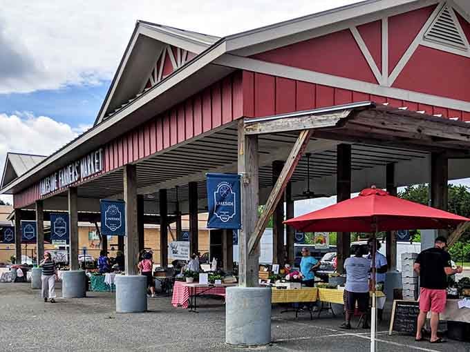 That red barn structure welcomes you like an old friend, promising fresh produce and handmade treasures under one charming roof.