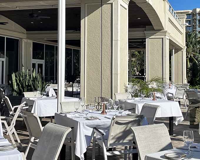 Crisp white linens flutter in the breeze on this elegant terrace where Gulf views steal the show from every angle.
