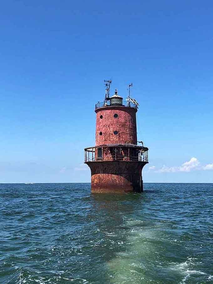 Standing in the bay like a rusty red castle, this lighthouse has weathered more storms than a soap opera.