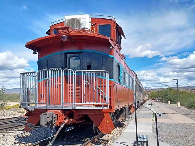The vintage caboose gleams in bold red and blue, its observation deck promising panoramic views of canyon country ahead.
