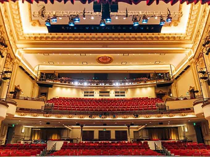 Rows of crimson seats face the ornate stage, where dreams come alive under glittering chandeliers above.