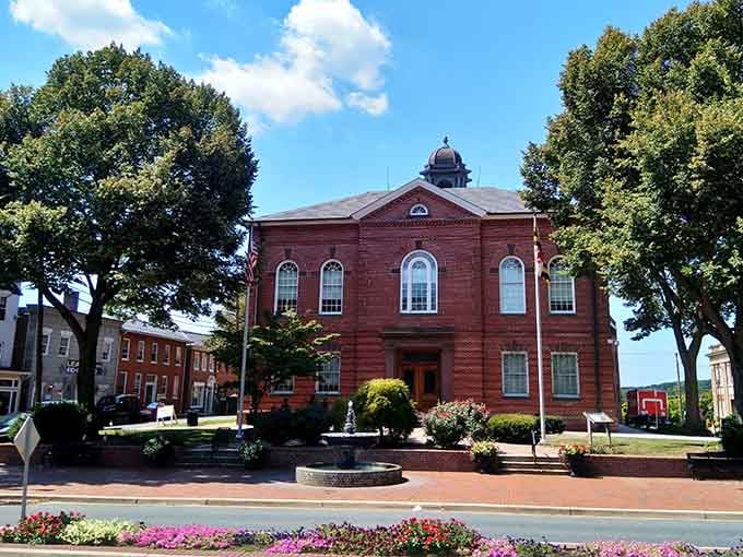 Red brick courthouse sits surrounded by flowers like a dignified elder statesman who still knows how to dress sharp.