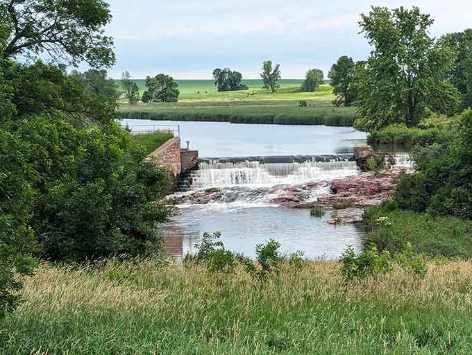 Water spills gently over the dam while green fields stretch toward the distant horizon.