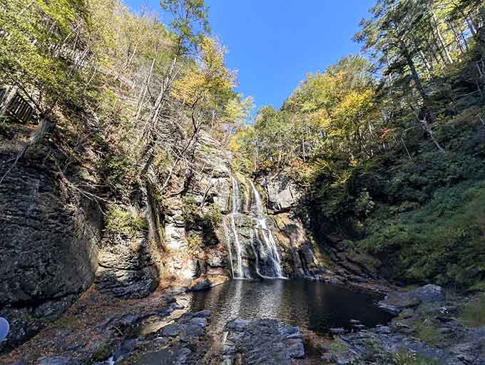 The falls nestle into their rocky amphitheater like a hidden treasure, surrounded by autumn's first golden touches.