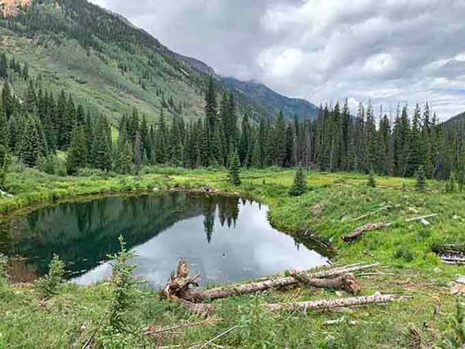 This peaceful meadow pool sits surrounded by evergreens, where soaking tired muscles becomes a high-altitude spiritual experience.