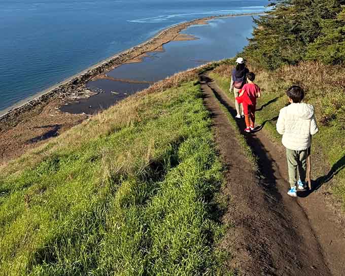 Three generations walk together along windswept cliffs, proving that the best family memories happen outdoors, not indoors.