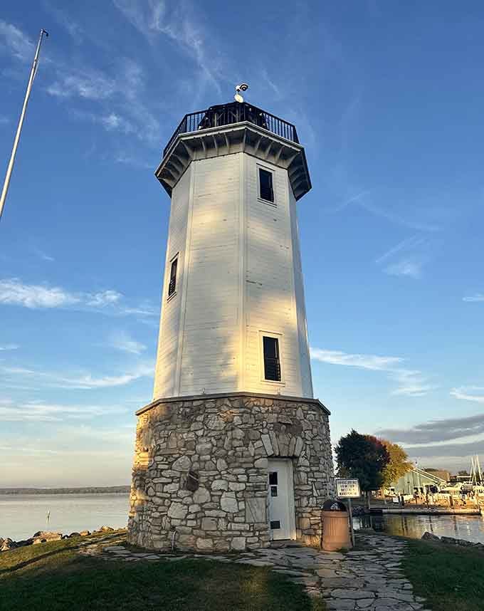 Golden hour light bathes the white tower in warmth, making the stone base glow like honey against the waterfront setting.