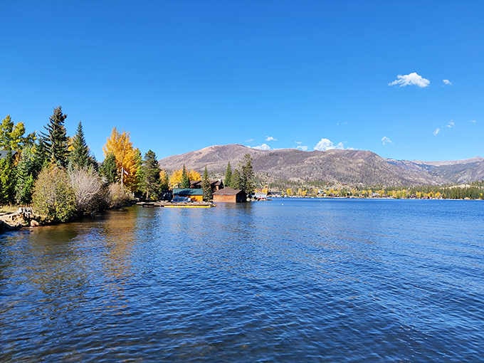 Autumn colors frame the sparkling lake as snow-capped peaks create a stunning backdrop for this alpine gem.