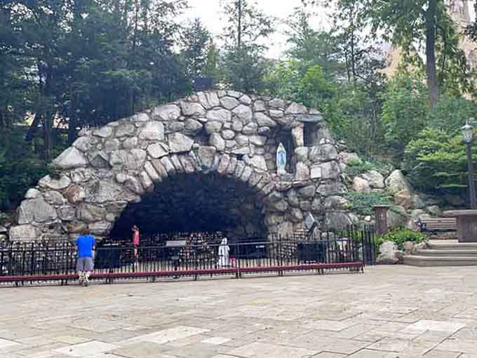 The rough-hewn stones of the grotto create a cave of contemplation where flickering candles dance across weathered walls.
