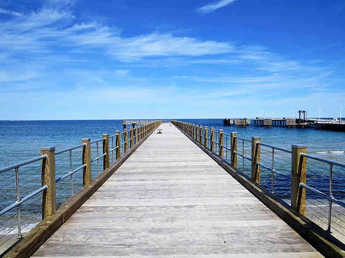 This pier stretches endlessly toward the horizon, inviting contemplative walks where ocean meets endless blue sky.