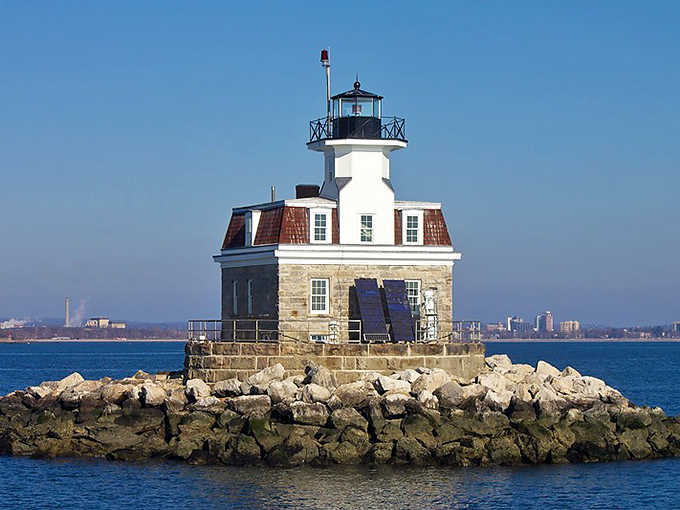 The mansard roof and stone foundation give this offshore guardian more character than most mainland houses could dream of.