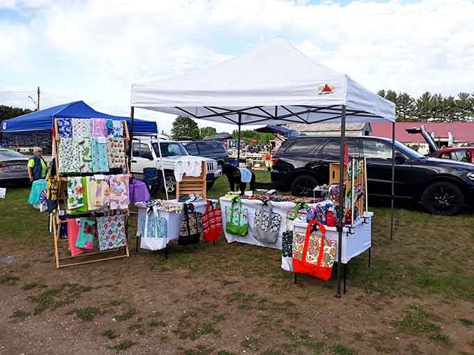 Colorful handmade bags and crafts brighten this outdoor booth where creativity meets commerce under a practical white canopy tent.