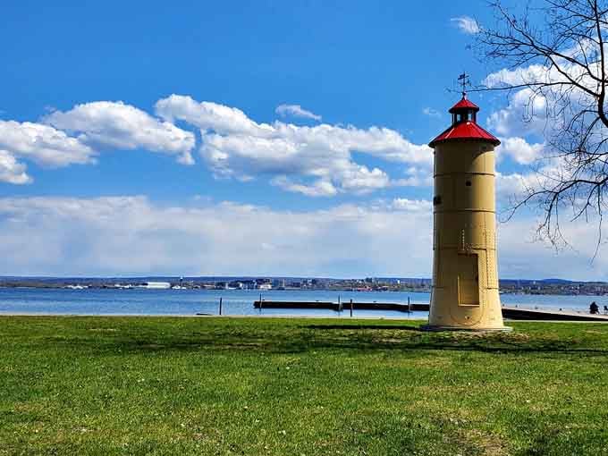 The cheerful yellow tower with its red cap looks almost toy-like against the vast blue expanse of Great Lake waters.