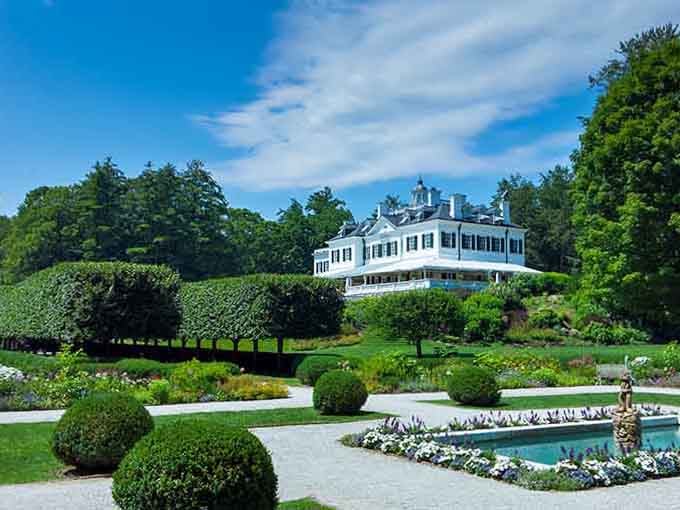 The formal gardens stretch toward the grand estate, where some say the author's spirit still appreciates her beloved design.